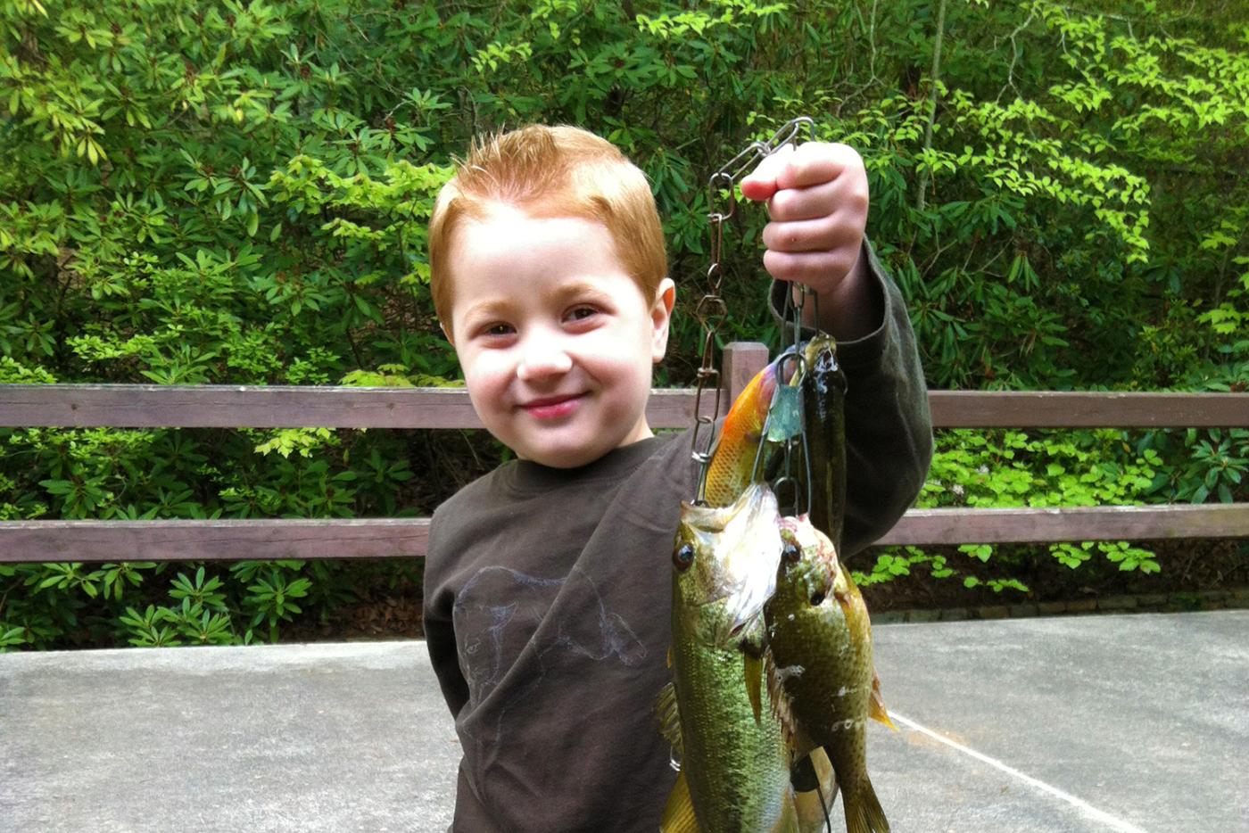 A boy holding up fish he caught at the park lake at Hanging Rock State Park